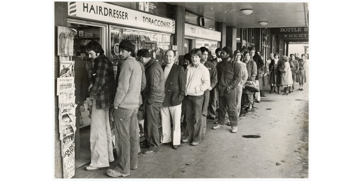 Queue of people outside a hairdresser and tobacconists